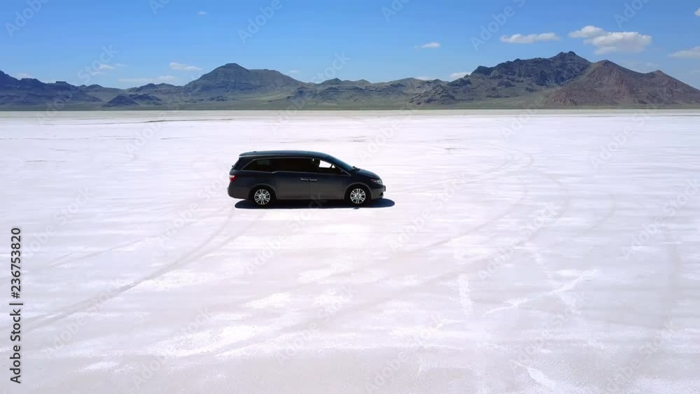 Drone flying sideways following silver minivan car driving in the ...