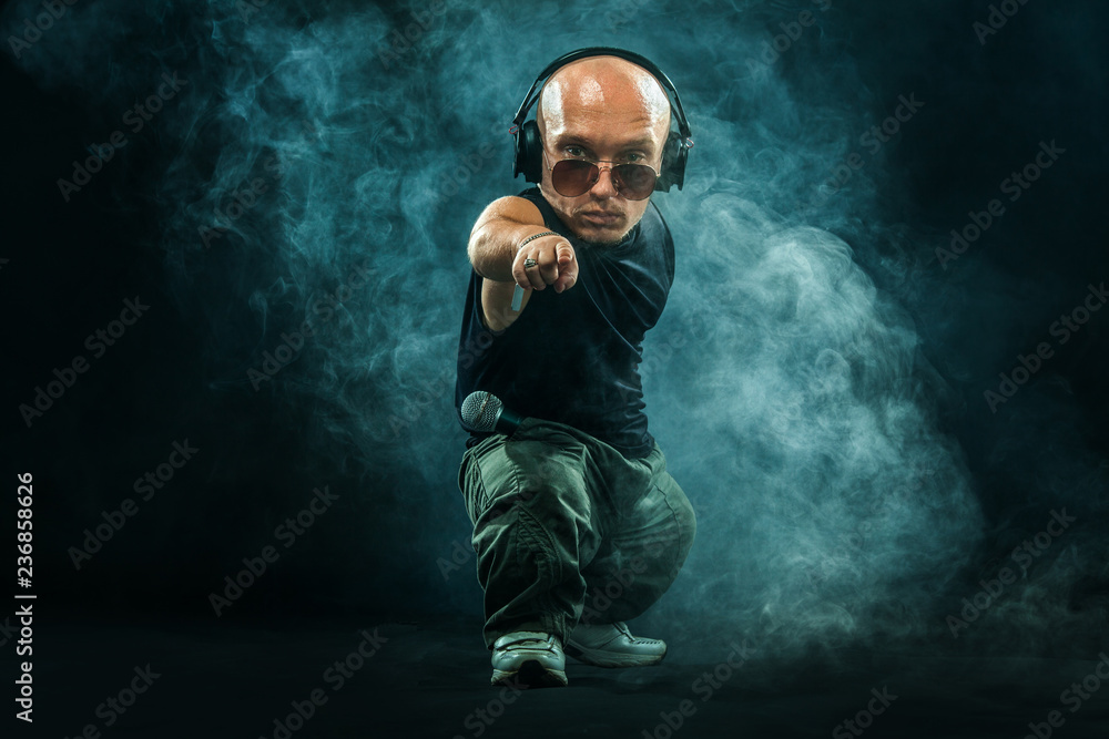 Portrait of stylish midget MC in with headphones and sunglasses posing ...