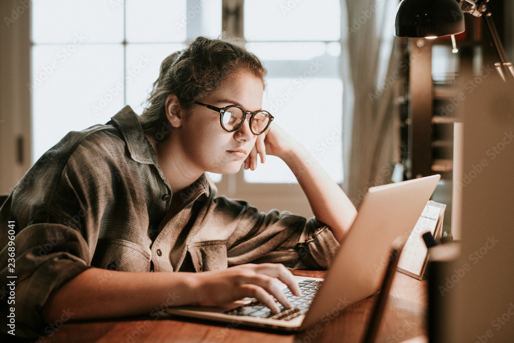 Teen girl doing homework on her laptop Stock Photo | Adobe Stock