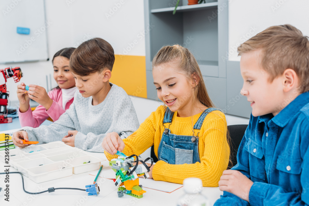 schoolchildren making electric robot at desk in stem education class ...