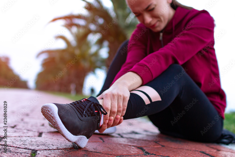 Foto de A young, fitness girl in sneakers and sportswear was injured ...