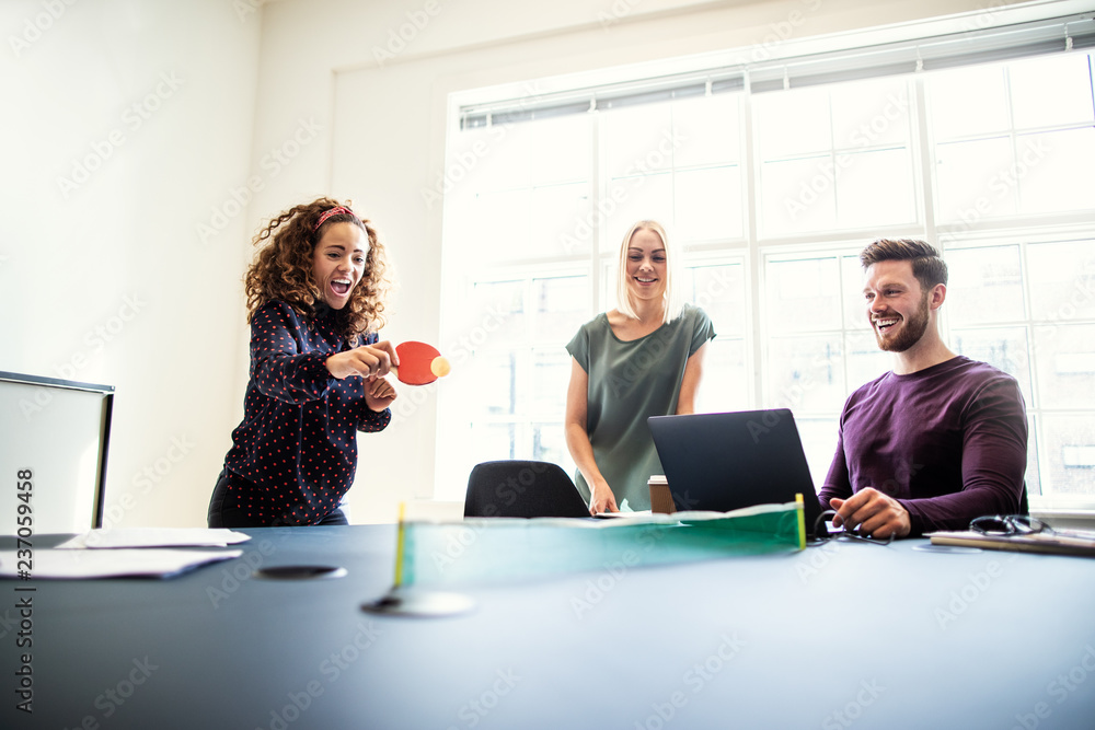 Laughing colleagues playing table tennis together in an office Stock ...