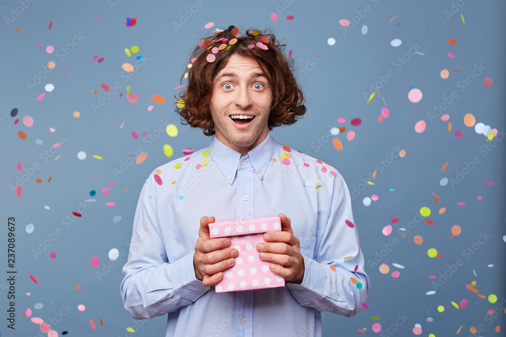 Surprised birthday man accepts congratulations, gets a gift in a pink ...