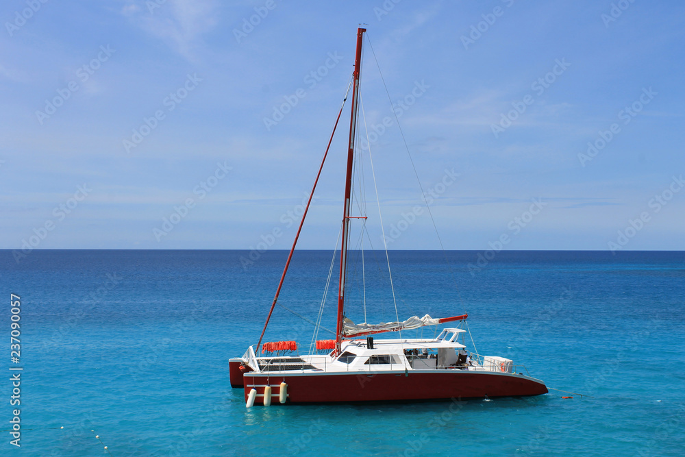 A Catamaran sits at anchor in the bay, Montego Bay, Jamaica. Green and ...