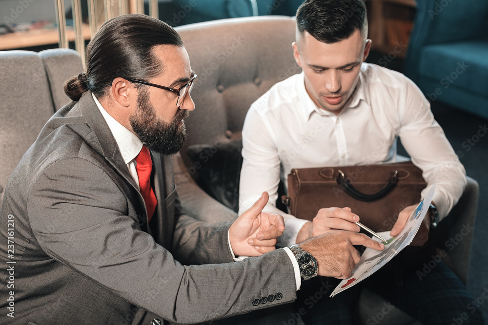 Bearded boss explaining working moments to his young trainee Stock ...