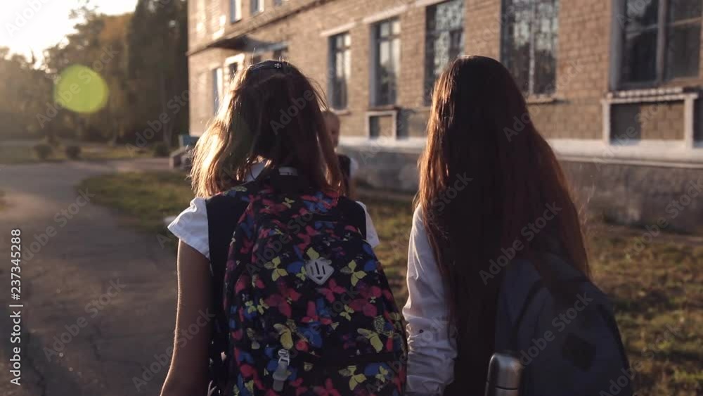 Two teen girls in the uniforms coming back from school home and walking ...