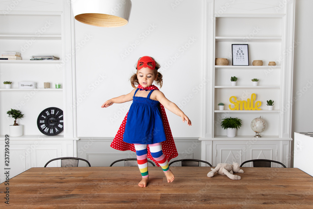 Little girl dressed up as superhero standing on kitchen table Stock ...