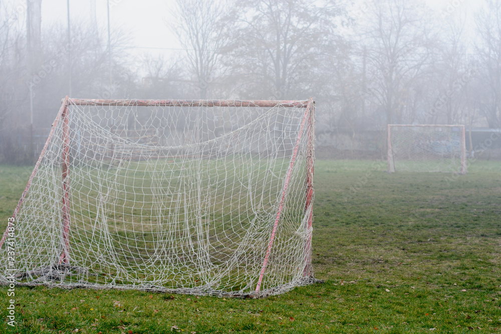 Old empty abandoned football field and gate with a tangled net in a ...