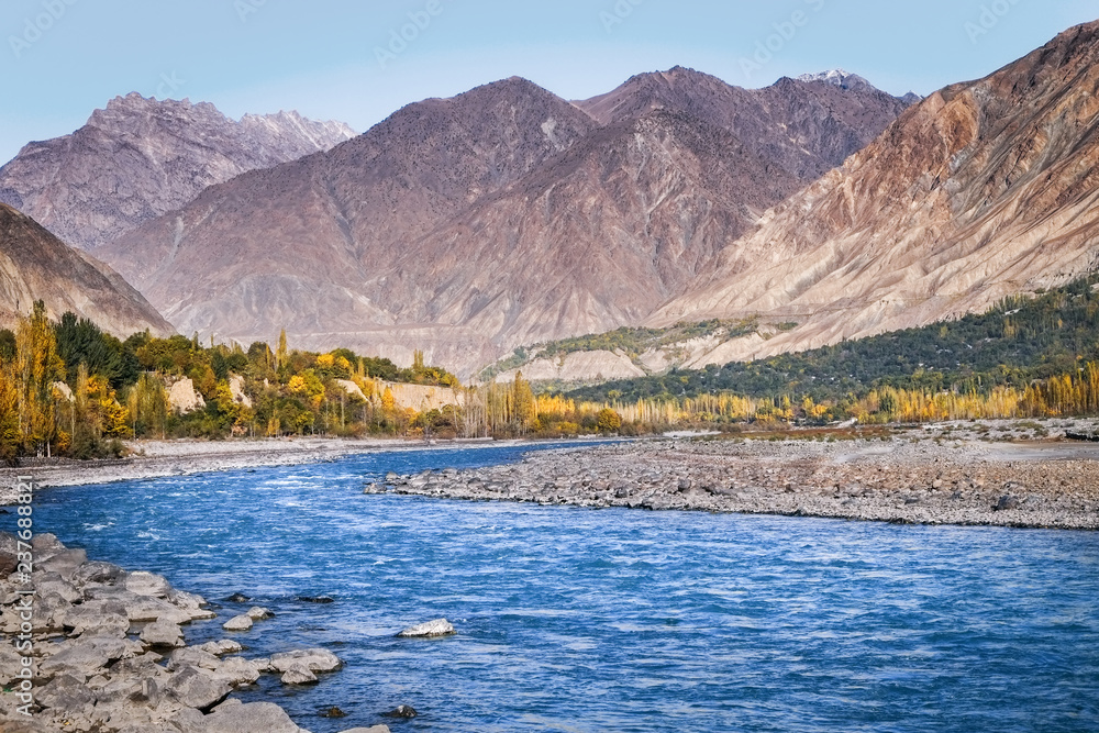 Flowing blue water of Gilgit River with mountains in the background ...