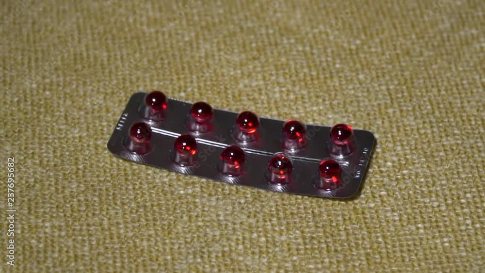 Pills. Medication closeup. Blister with red round capsules slowly fall ...