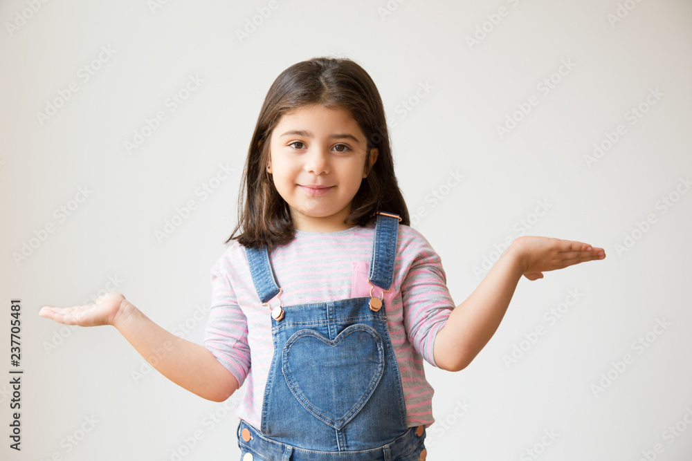 Cheerful Latin kid with shrug gesture asking something and looking at ...