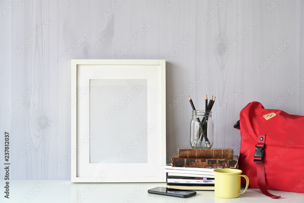 Desktop with mockup posters, red bag, supplies on white table. Student ...