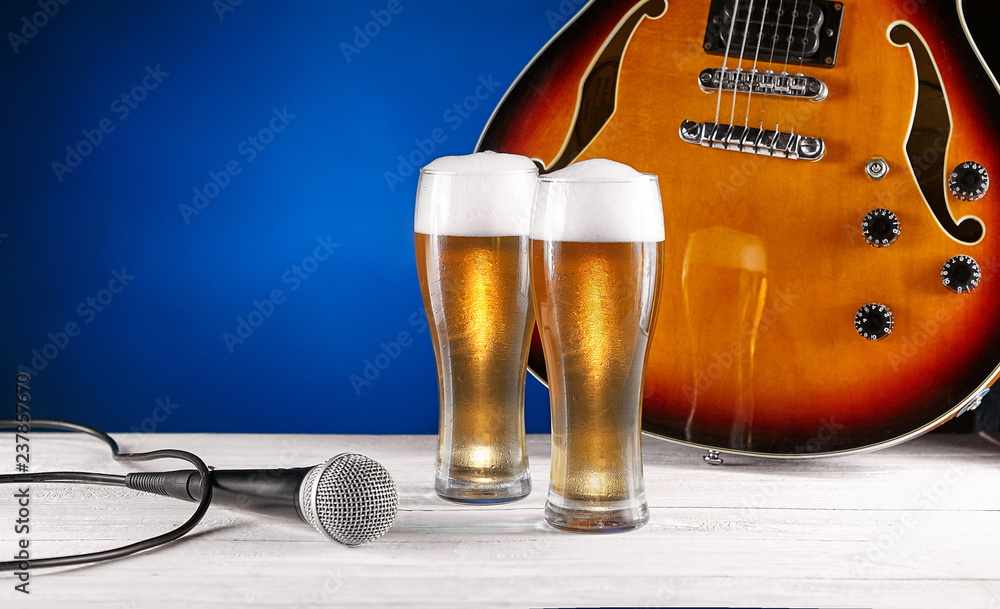 Two glass beer and microphone near electric jazz guitar on white wooden ...