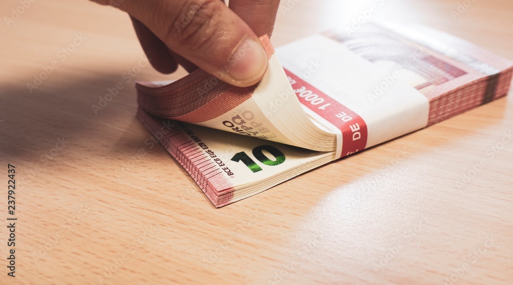 Female fingers counting a stack of 10 Euro notes on a pine desk. foto ...