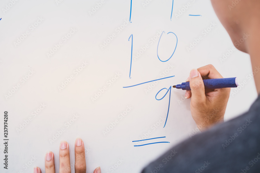 Rear view of Asian boy solving solution addition sum and substraction ...