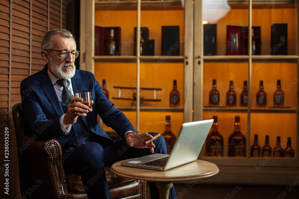 Well-dressed experienced caucasian old-aged CEO relaxing with cigar and ...