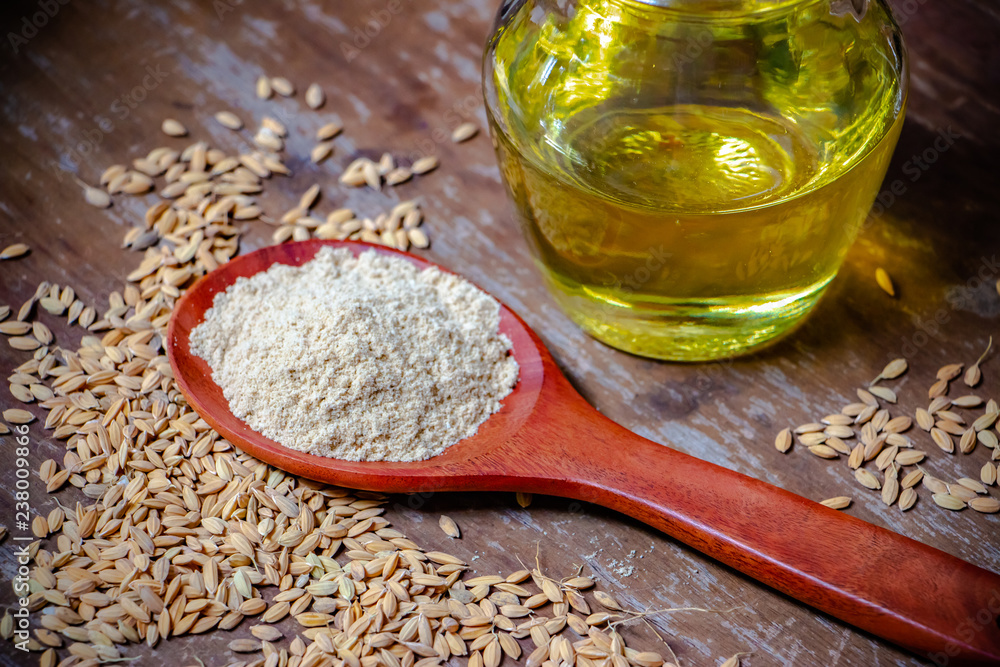 Rice bran oil in a jar with raw rice and chaff on wooden background ...