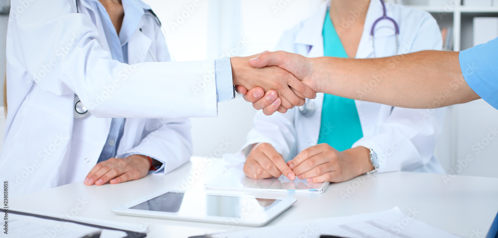 Two doctors shaking hands to each other at meeting. Teamwork and ...
