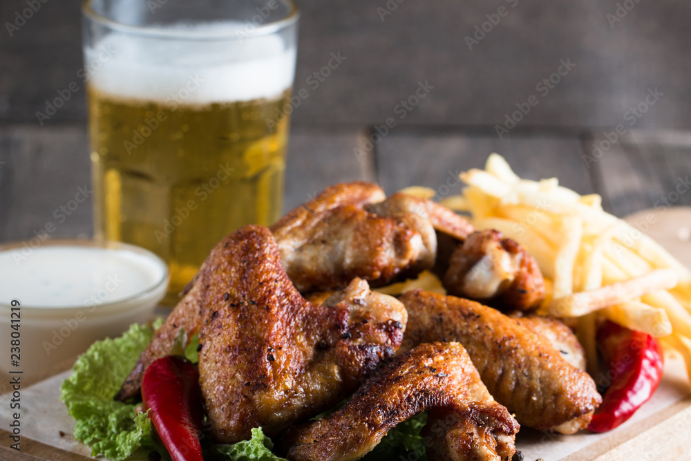 Close-up photo of bbq chicken wings with fries and beer. Barbeques meat ...