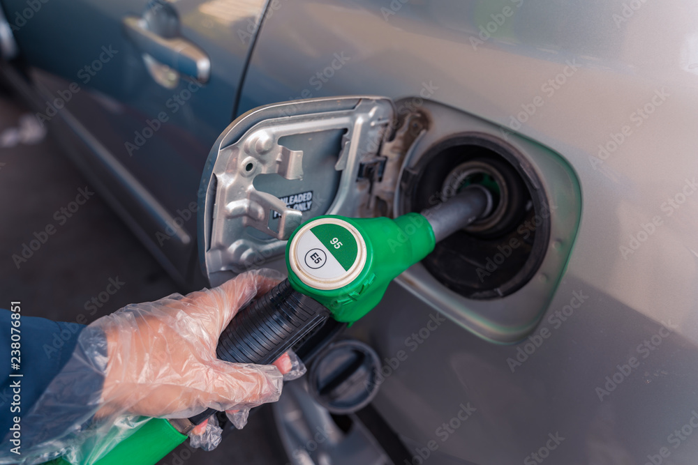 ..Fuel pistols at european Petrol station. Woman's hand in plastic ...