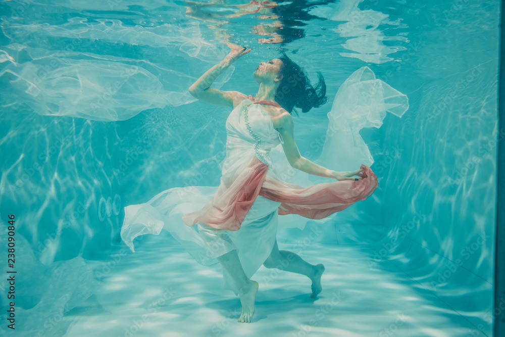 beautiful model girl swimming underwater in feminine long white and ...