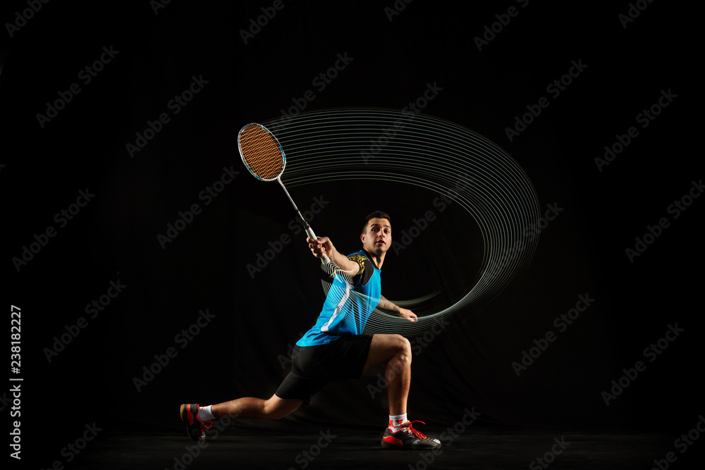 Young man playing badminton over black studio background. Fit male ...