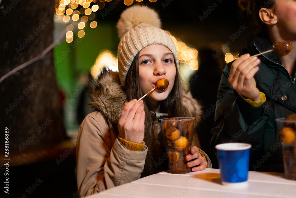 Cute teenager eating traditional fritula at Christmas market in Zagreb ...