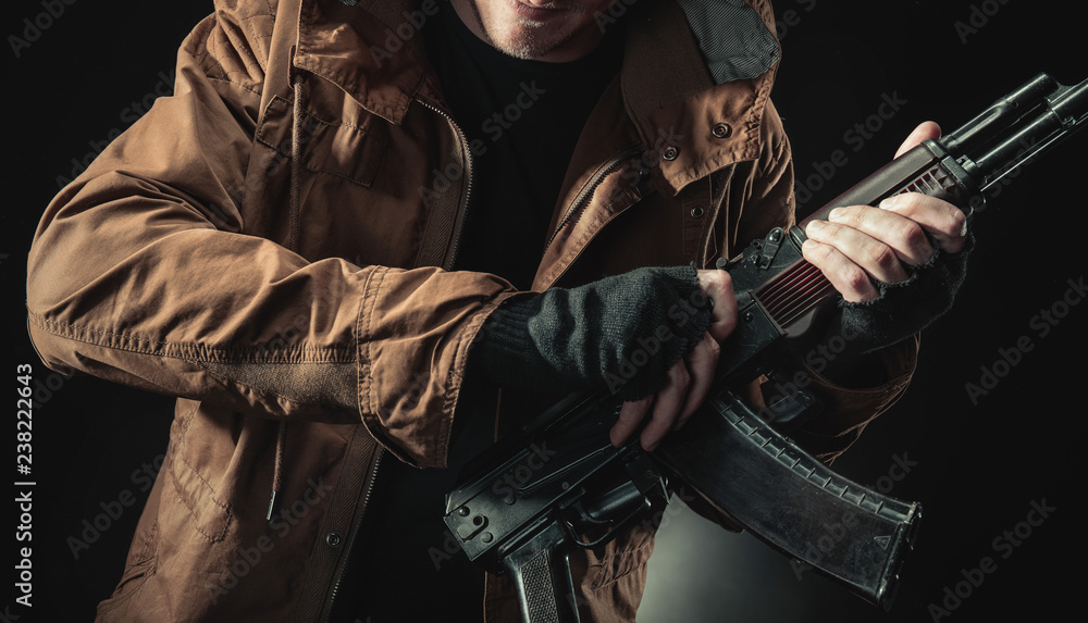 Dangerous armed terrorist with mask and machine gun on dark background ...