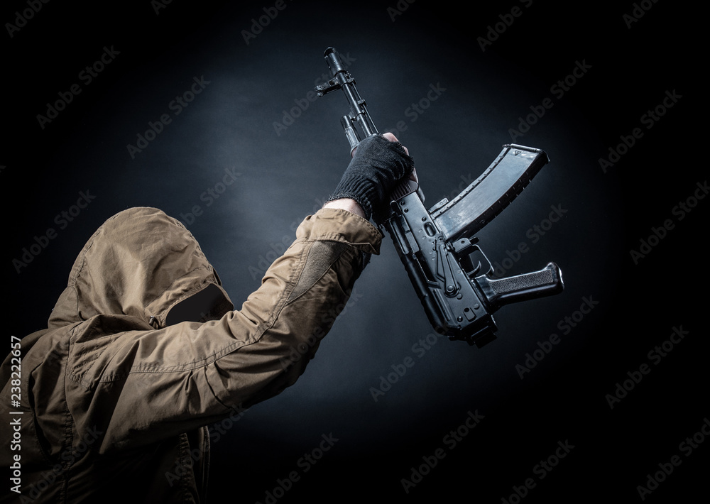 Dangerous armed terrorist with mask and machine gun on dark background ...