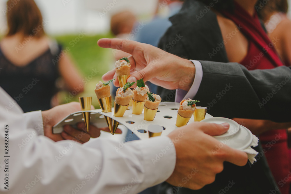 Wedding guest taking cone canape from waiter Stock Photo | Adobe Stock