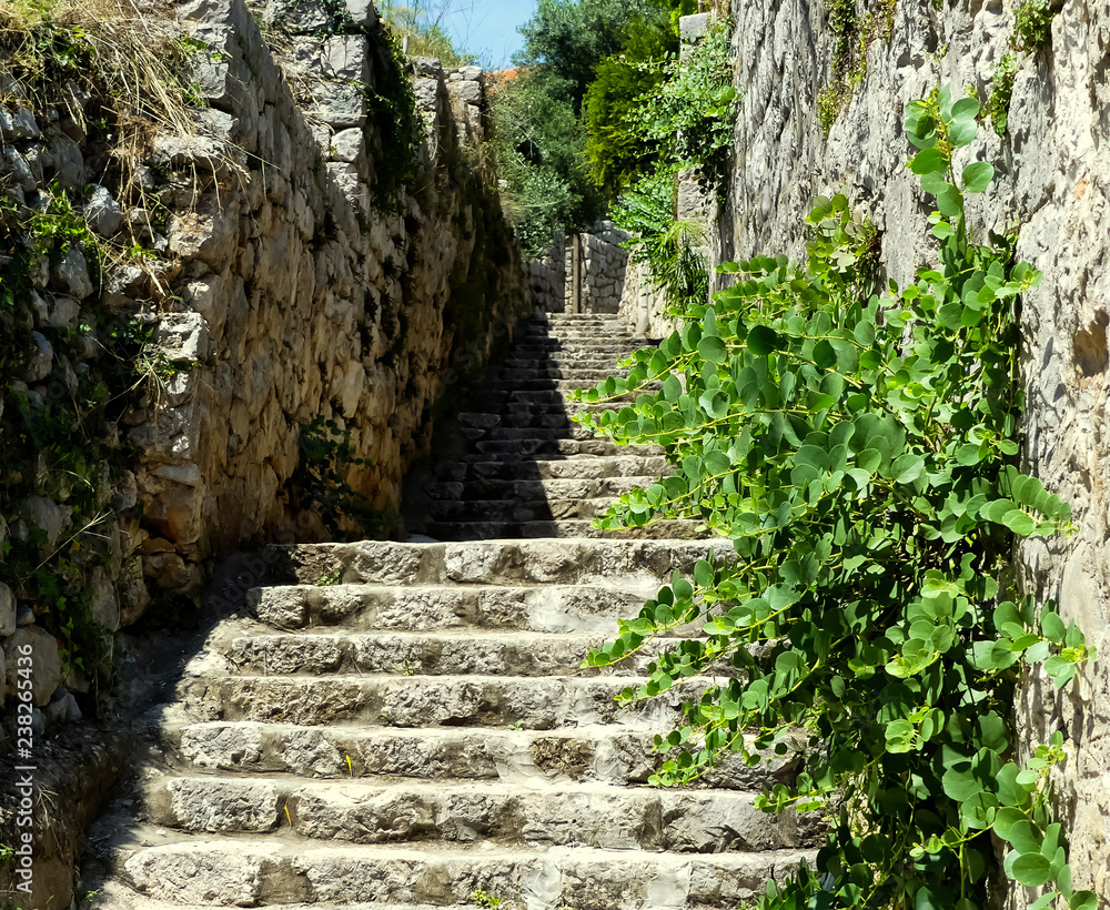 Isolated stone, stepped footpath rising past stone building and wall ...