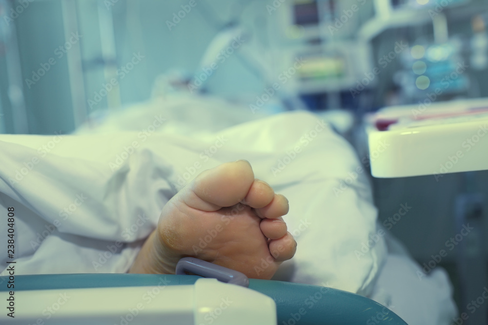 Foot of a suffering patient in a hospital bed as a symbol of illness ...