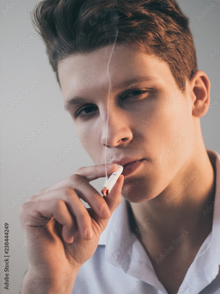 Young handsome guy smoking a cigarette, studio shooting. Stock Photo ...