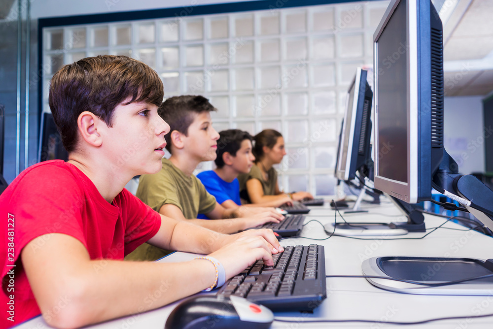 Side view of teacher with students using computers in classroom Stock ...