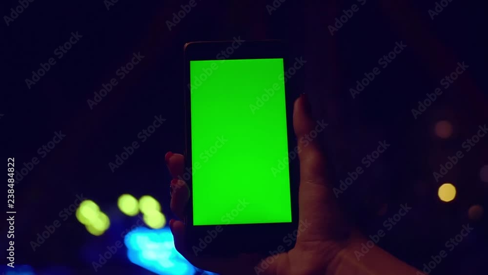 Hand young woman holding phone with green screen background blurred ...