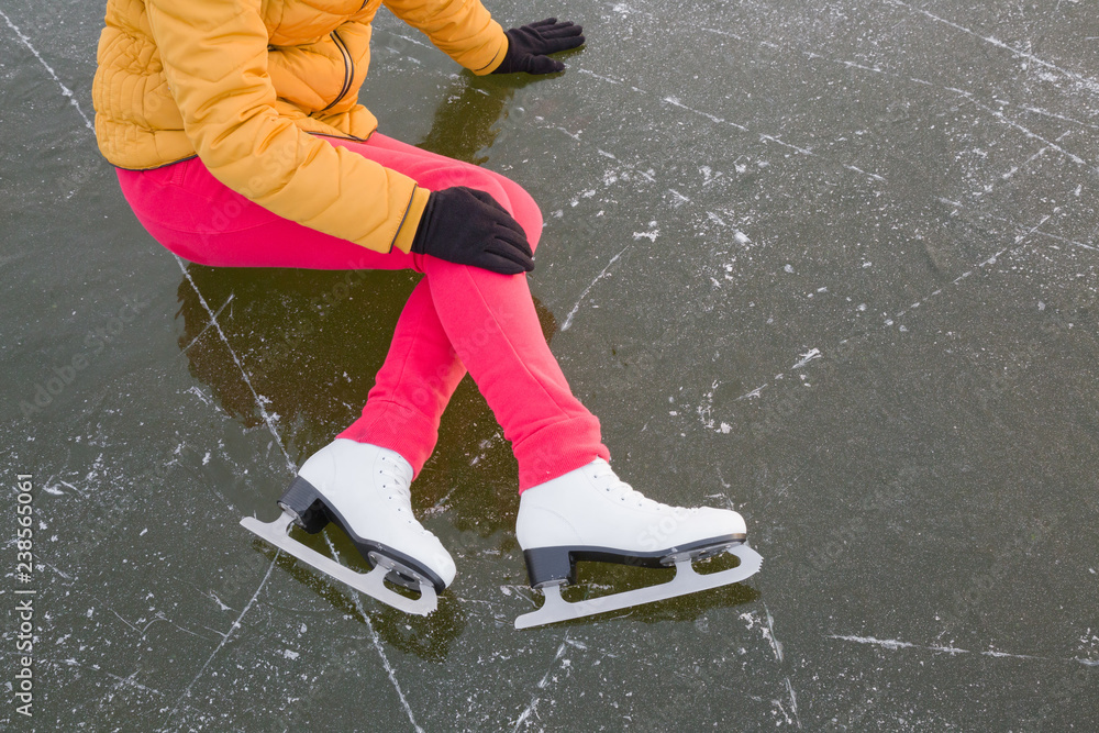 Young woman fallen on frozen lake during ice skating time in winter day ...