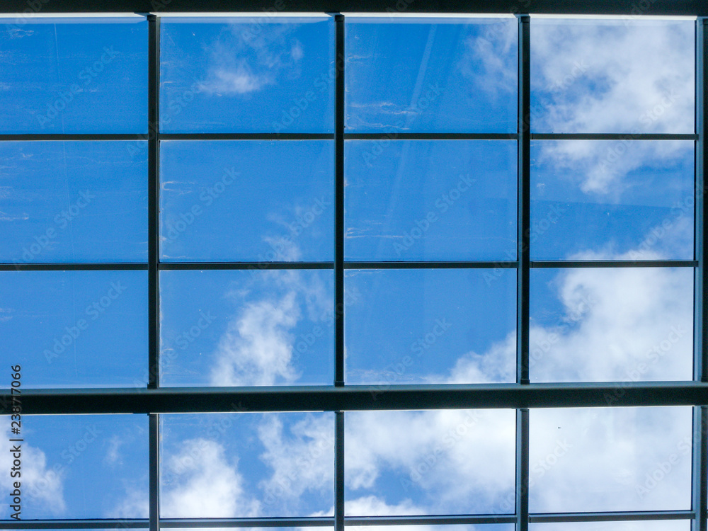 Blue sky with white clouds through the window in the ceiling of a large ...