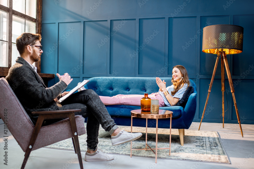 Young woman visiting male psychologist lying on the comfortable couch ...