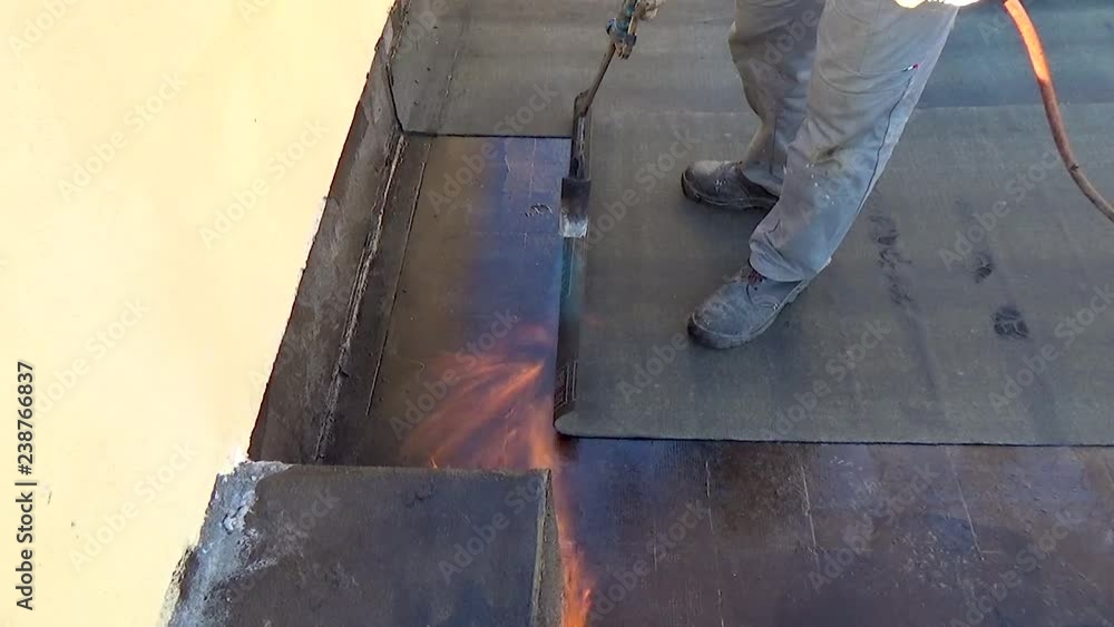 Worker performs sealing overlapping bitumen sheets on the flat roof of ...
