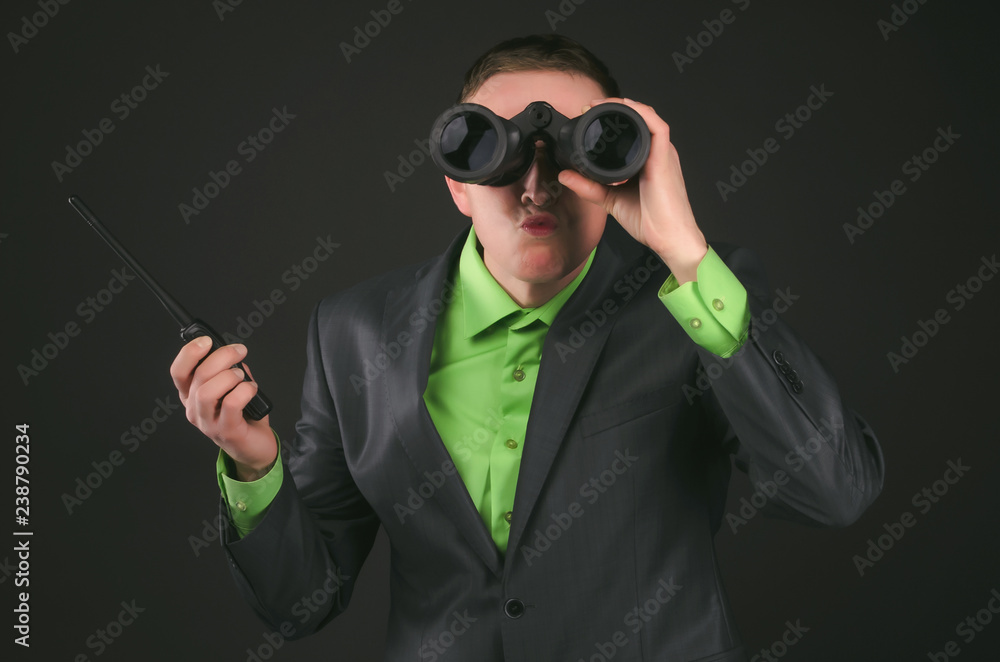 Spy or face control agent is looking through a binoculars in his hand ...