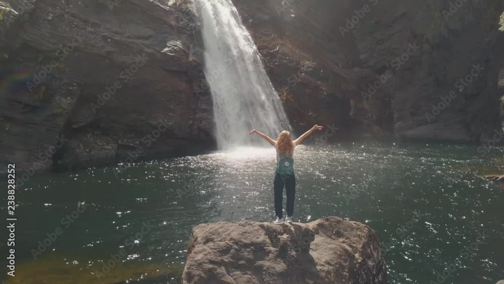 Beautiful female model standing under a multi level waterfall cascading ...
