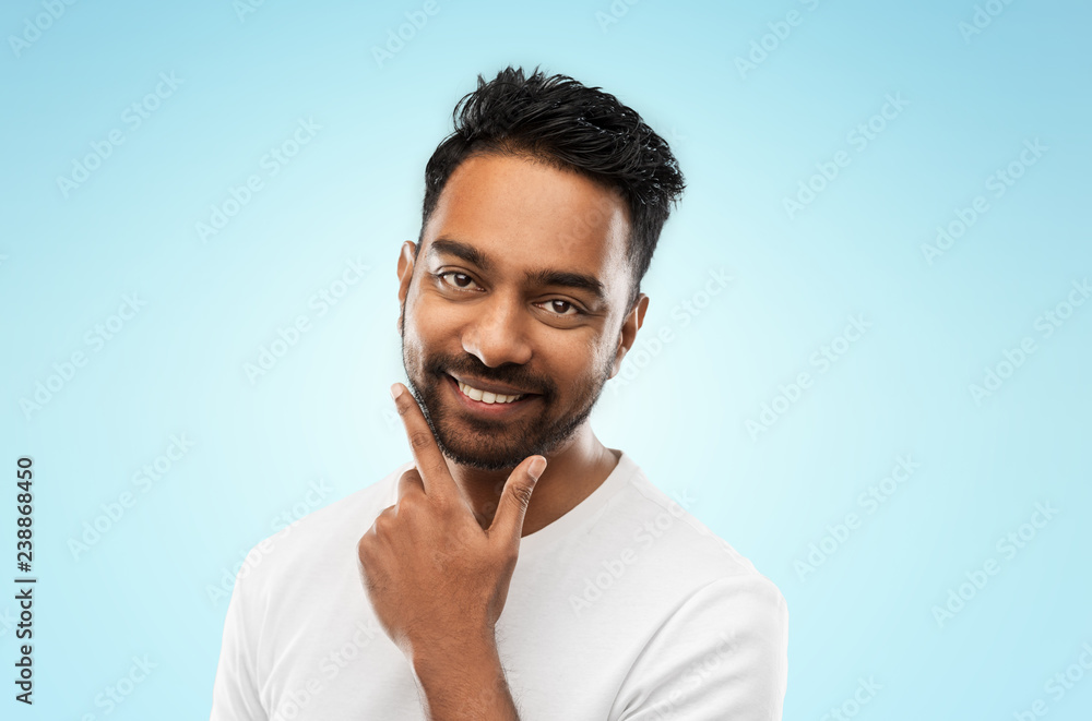 grooming and people concept - smiling indian man touching his beard ...