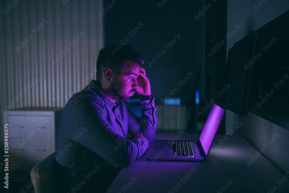 Young concerned bearded Caucasian businessman looking at laptop and ...