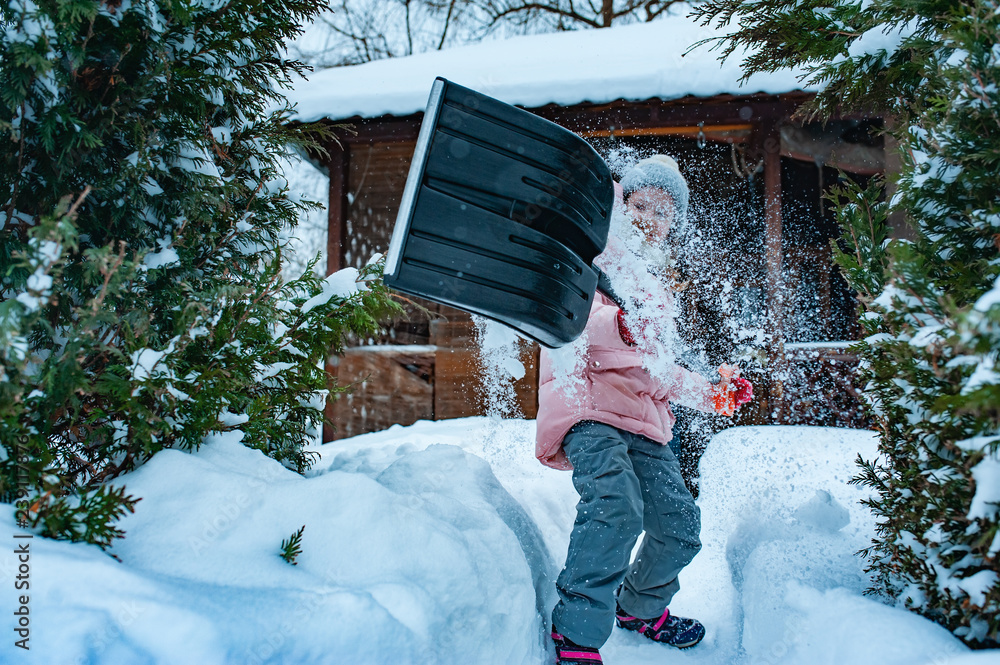 kid girl helping to clean pathway from snow with showel. Child playing ...
