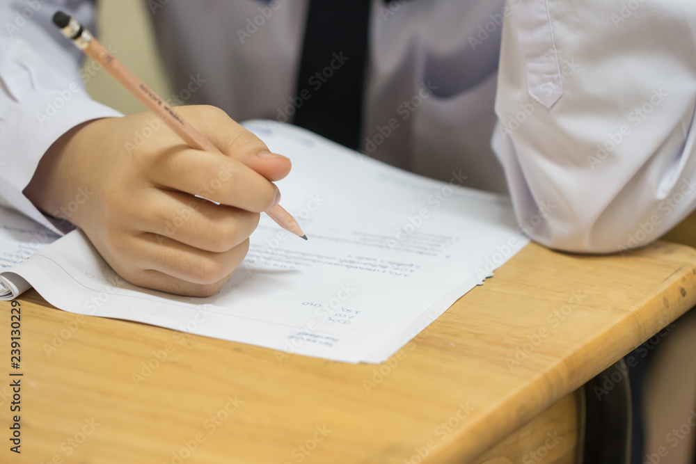 Students using pencil reading information on white paper in high school ...