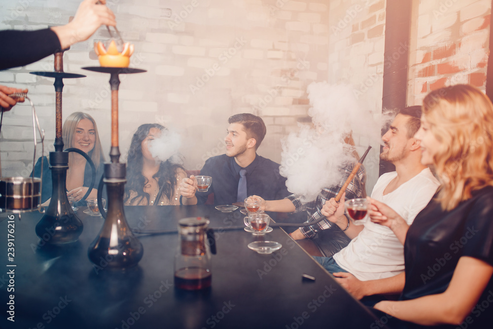 Corporate party. Colleagues relax in hookah, smoking, and drink tea ...