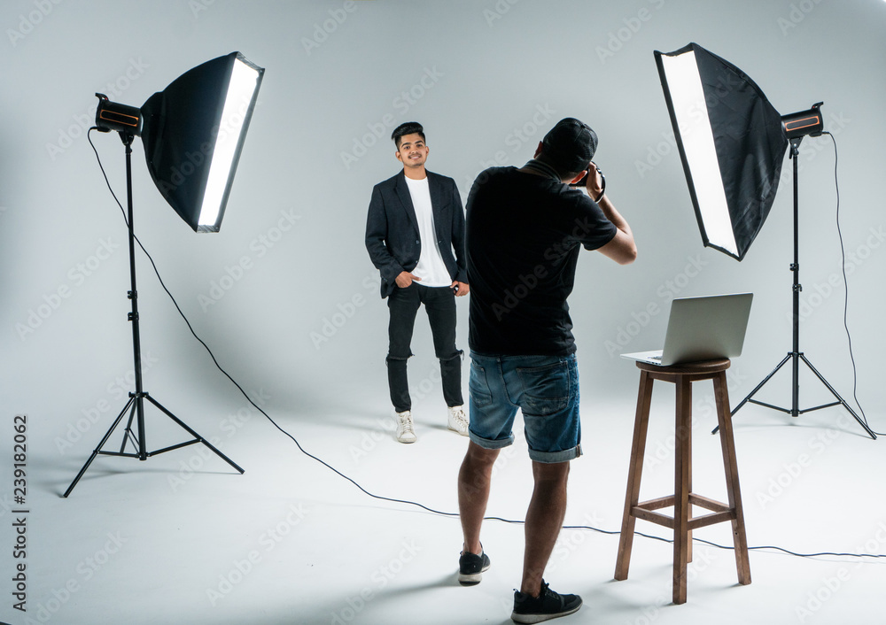 Photographer shooting model in studio with softboxes. Young man ...