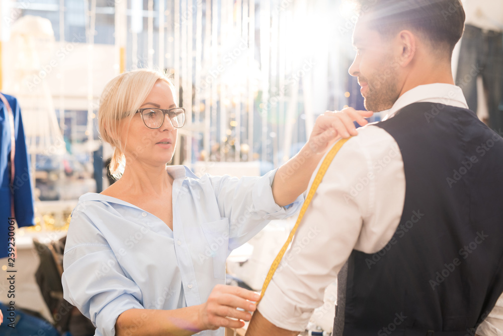 Waist up portrait of female tailor measuring client while fitting ...