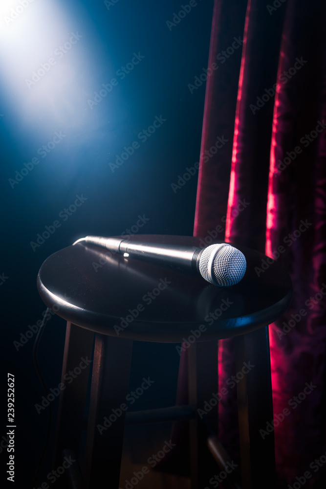 microphone on a wooden stool on a stand up comedy stage with reflectors ...