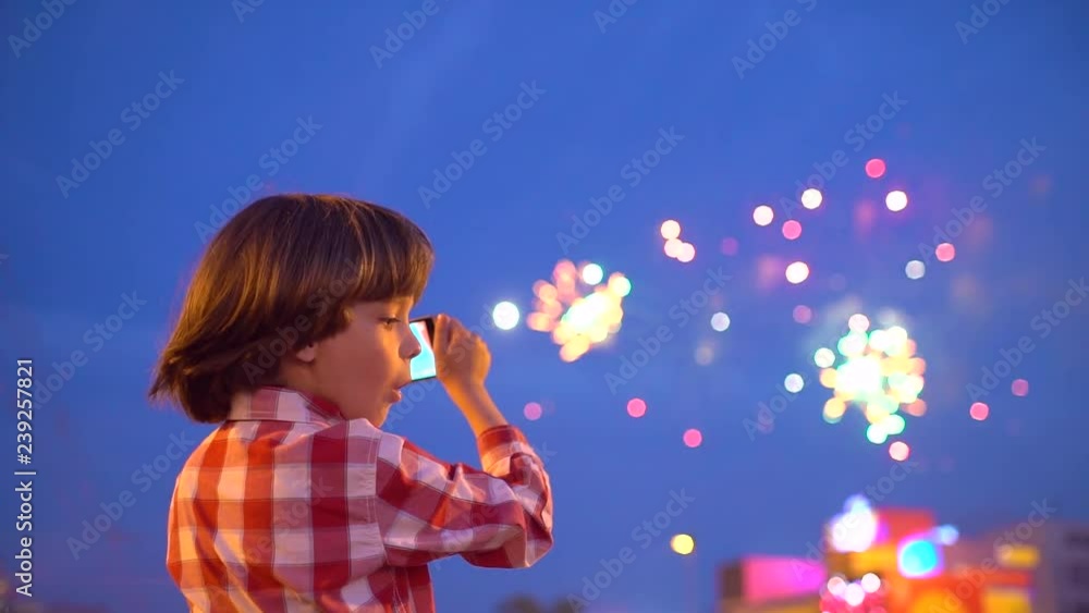 Little boy child filming pictures of beautiful fireworks in night sky ...